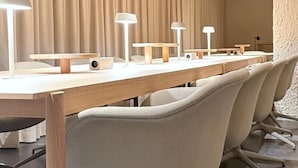 Uma sala de conferências com uma mesa comprida, várias cadeiras e diversos abajures.