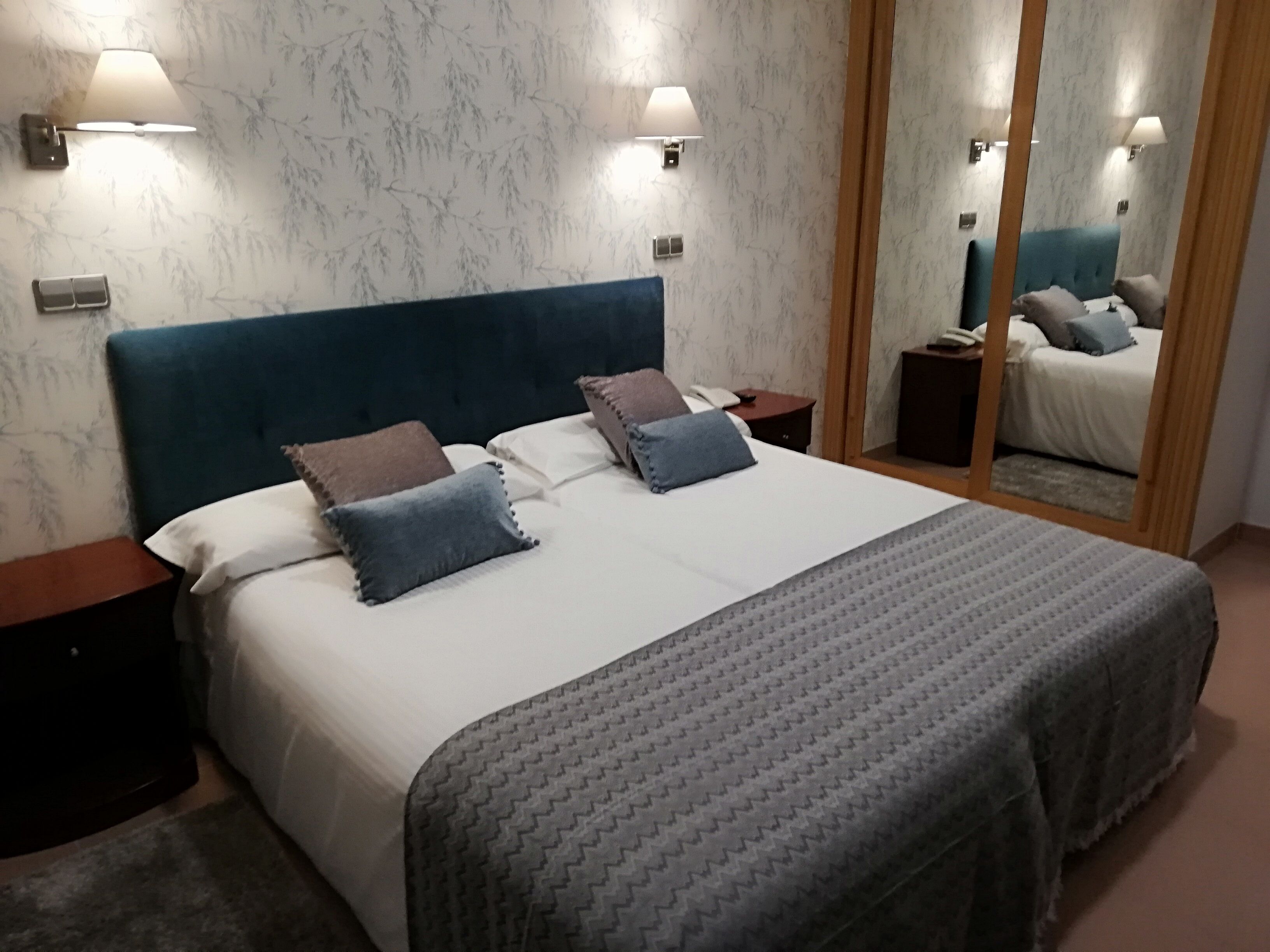 Quarto moderno com uma cama grande, duas mesas de cabeceira e um espelho.