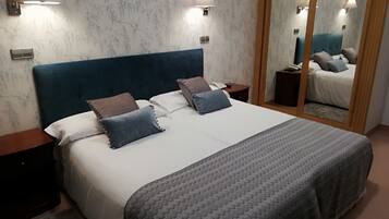 Quarto moderno com uma cama grande, duas mesas de cabeceira e um espelho.