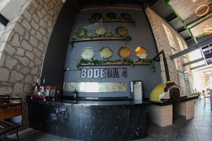 Uma área de recepção com parede de pedra, balcão e forno a pizza.