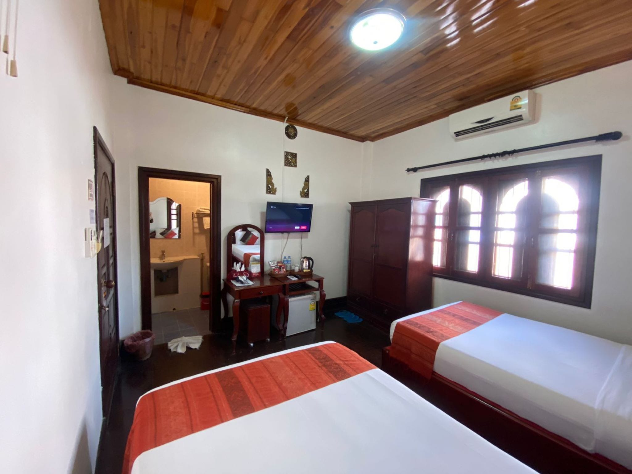 Quarto de hotel com duas camas, uma escrivaninha, televisão e guarda-roupa.