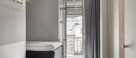Quarto com cama, varal e vista para a varanda.