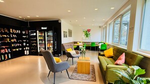 Uma área de estar moderna com assentos, uma máquina de café e prateleiras com diversos objetos.