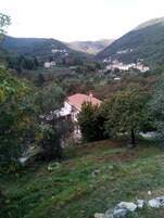 Um vale com um edifício de telhado vermelho, rodeado de vegetação e colinas.