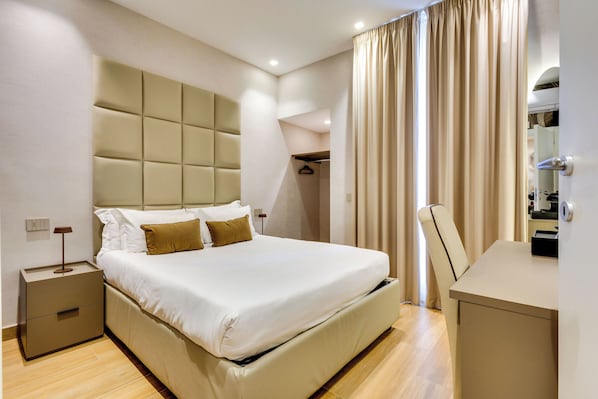 Quarto de hotel moderno com uma cama grande, uma mesa de cabeceira, uma escrivaninha e um guarda-roupa.