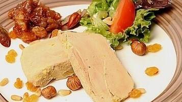 Um prato com uma fatia de carne, nozes e uma salada.