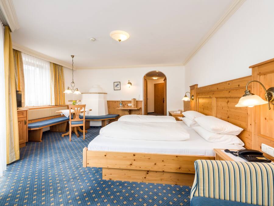 Quarto de hotel com uma cama grande, uma escrivaninha, uma cadeira e uma mesa pequena.