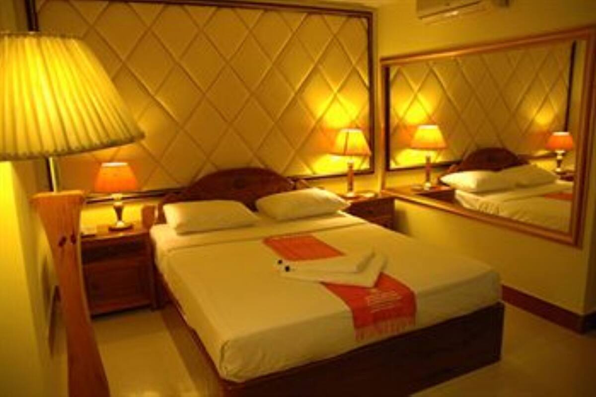 Quarto de hotel com uma cama grande, duas mesas de cabeceira e um espelho sobre a cama.