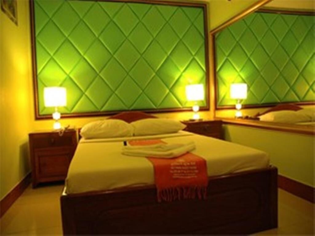 Quarto de hotel com uma cama grande, duas mesas de cabeceira e cabeceira verde.