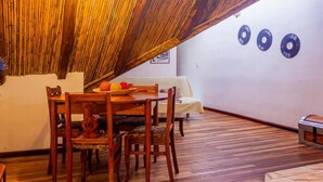 Uma sala de jantar com uma mesa e cadeiras de madeira, um sofá branco e uma parede com três discos de vinil.