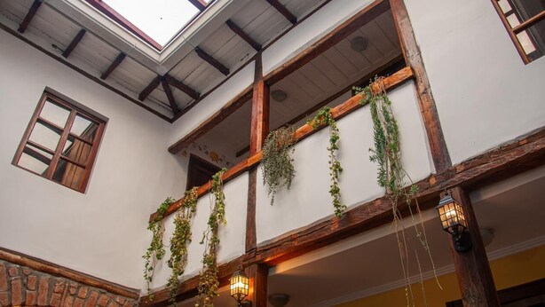 Um edifício com teto abobadado, vigas de madeira e uma janela com moldura de madeira.