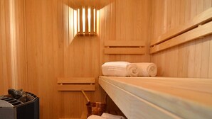 Uma sauna de madeira com bancos, um banco com um balde e toalhas sobre um banco.