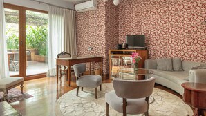 Uma sala de estar moderna com sofá, cadeiras, uma mesa de centro de vidro e televisão.