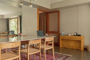Uma área de jantar moderna com mesa de vidro, cadeiras de madeira e tapete tecido.