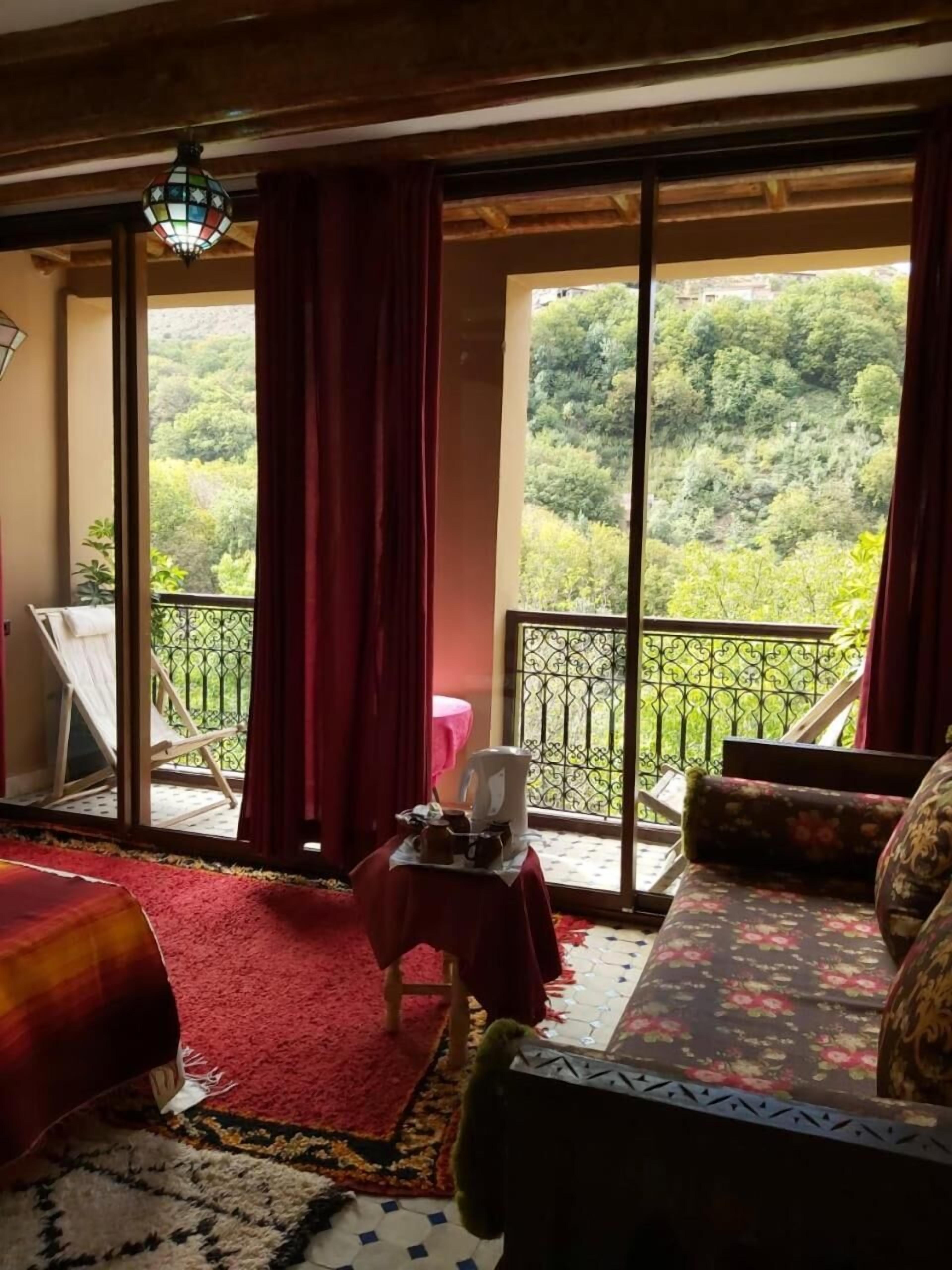 Varanda com tapete vermelho, sofá, mesa com cafeteira e uma cadeira.