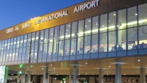 Um terminal de aeroporto internacional com fachada de vidro moderna e uma placa grande com a inscrição 'INTERNATIONAL AIRPORT'.