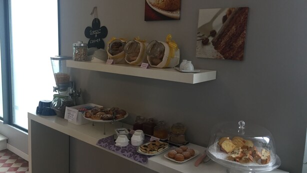 Exposição de doces e pães numa confeitaria, com uma máquina de café.