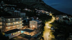 Zona residencial com casas, piscina e estrada que sobe a colina.