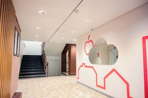 Um interior moderno com escada, parede com padrões geométricos e teto com iluminação embutida.
