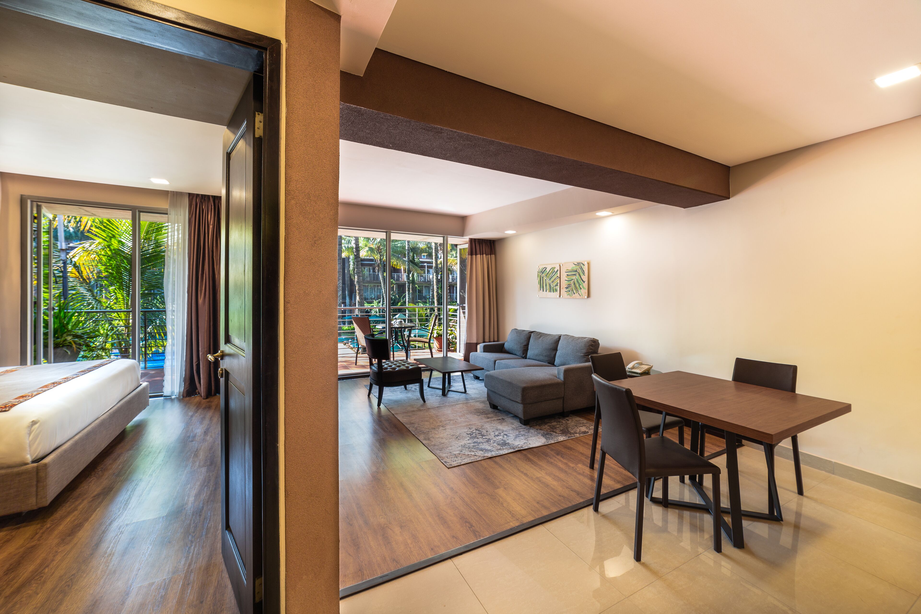 Quarto de hotel moderno com cama, sofá, mesa de jantar e cadeiras.
