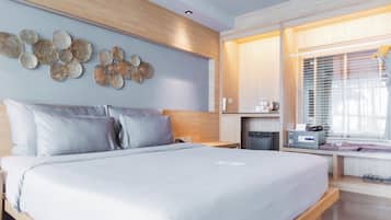 Quarto de hotel moderno com uma cama grande, uma pequena mesa de trabalho e um objeto decorativo fixado na parede.