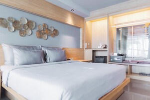Quarto de hotel moderno com uma cama grande, uma pequena mesa de trabalho e um objeto decorativo fixado na parede.