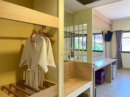 Quarto de hotel com guarda-roupa de madeira, espelho, escrivaninha e vista para o exterior.
