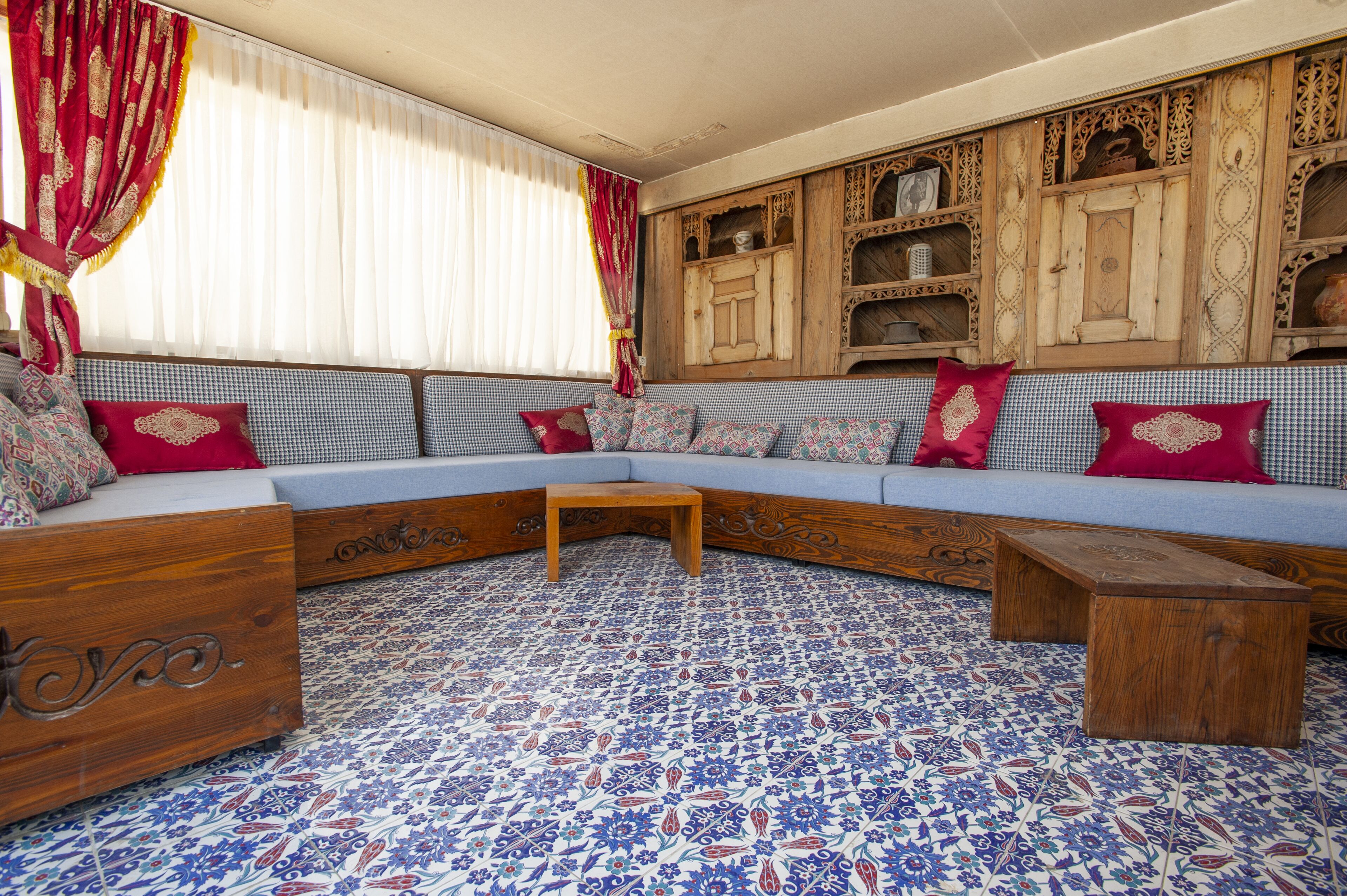 Uma sala de estar acolhedora com um sofá quadriculado, mesas laterais de madeira e ladrilhos de chão estampados.