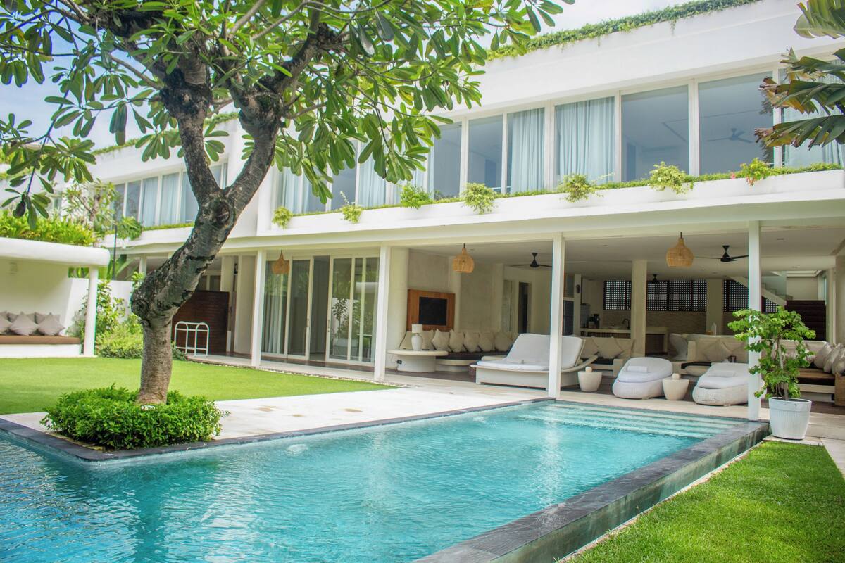 Uma casa moderna com piscina, área de estar externa e um alpendre coberto.