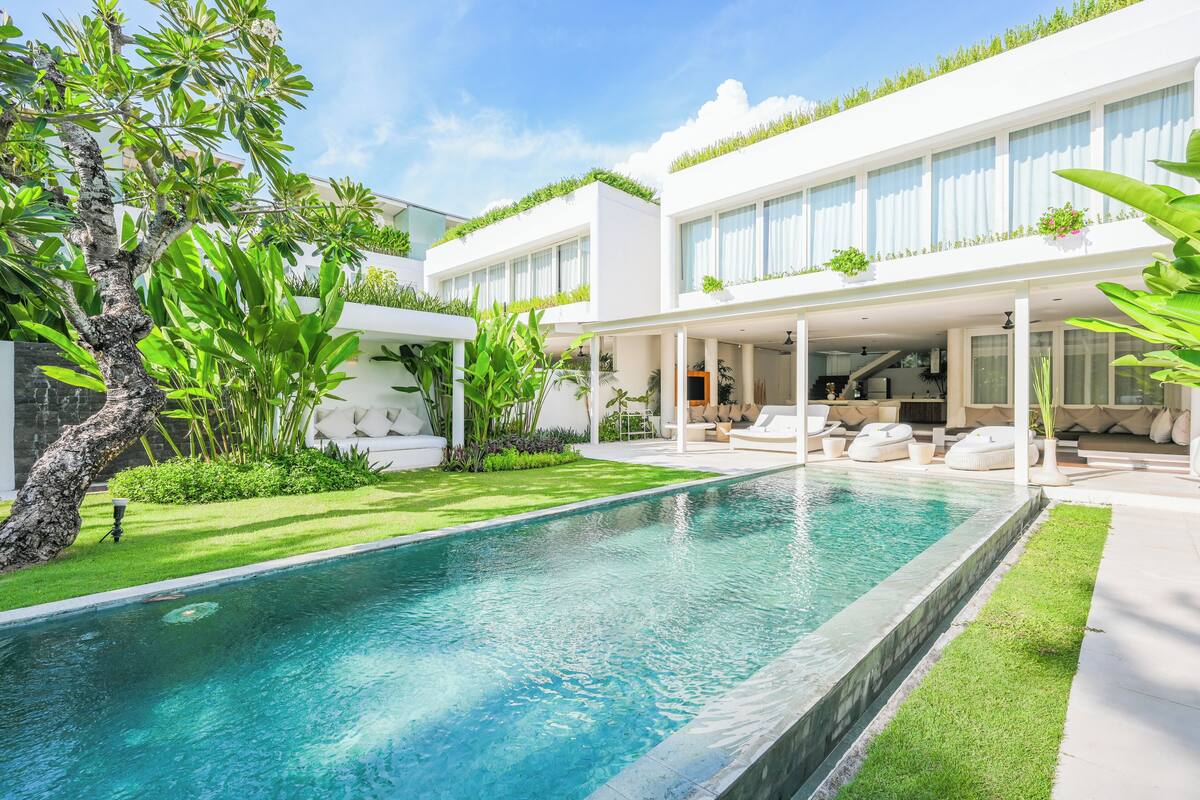 Uma casa moderna com piscina, vegetação exuberante e área de estar coberta ao ar livre.