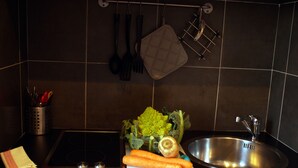 Uma cozinha com fogão, pia e diversos utensílios.