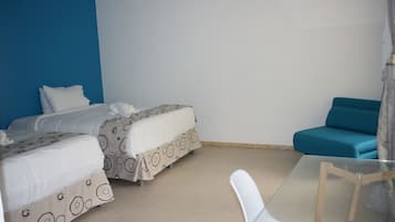 Quarto com duas camas, uma mesa de vidro e uma cadeira azul.