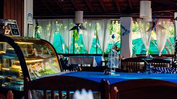 Um restaurante com toalha de mesa azul, cadeiras de madeira e uma vitrine de vidro.