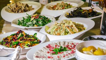 Diversos pratos em uma mesa, incluindo saladas, carnes e uma sobremesa.