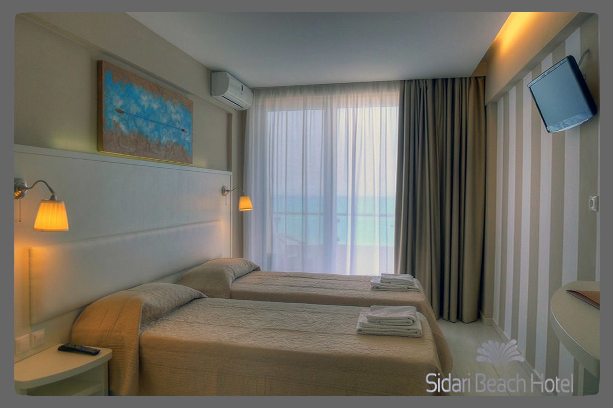 Quarto de hotel com duas camas, televisão e uma pintura na parede.