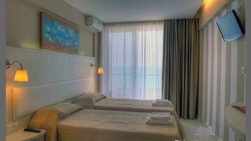 Quarto de hotel com duas camas, televisão e uma pintura na parede.