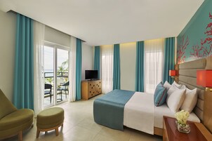 Quarto de hotel com cama, televisão, escrivaninha e vista para o exterior.