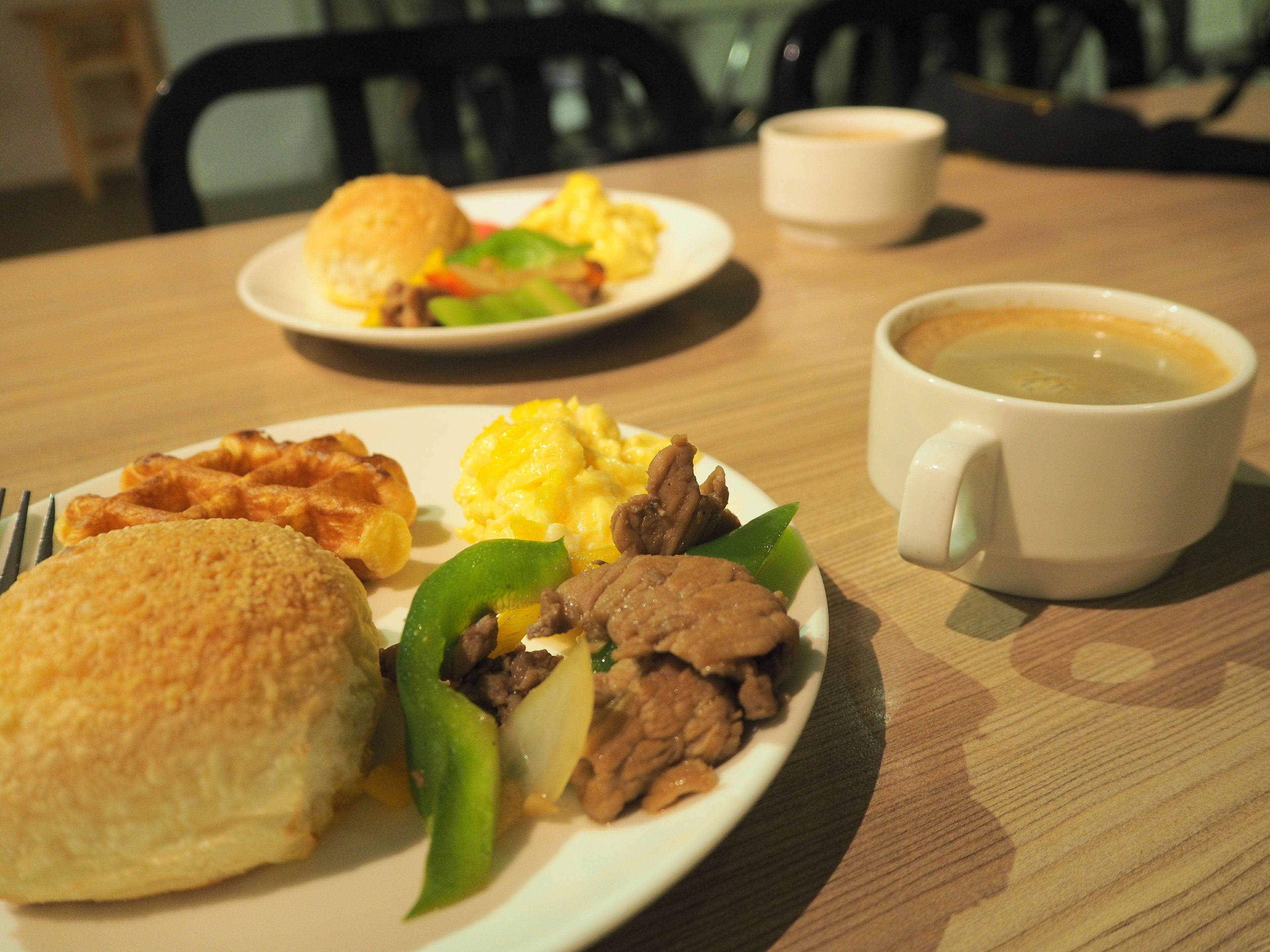 Um prato com comida, uma xícara de café e um prato com ovos e legumes.