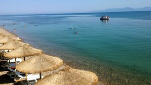 Uma praia com águas cristalinas, um barco e guarda-sóis de palha.