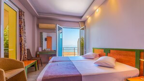 Quarto de hotel com duas camas, uma escrivaninha, uma cadeira e vista para o exterior.