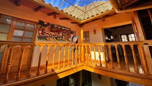 Quarto com varanda de madeira, um amplo claraboia de vidro e um mural na parede.