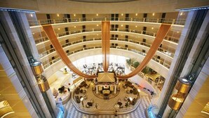 Um hall de hotel com vários níveis, área de estar central e design moderno.
