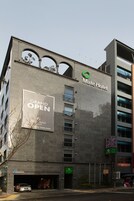 Um hotel com um grande letreiro 'Grand Open', design arquitetônico moderno e entrada de estacionamento.