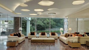 Uma sala de estar ampla com uma grande janela, móveis modernos e um design de teto singular.