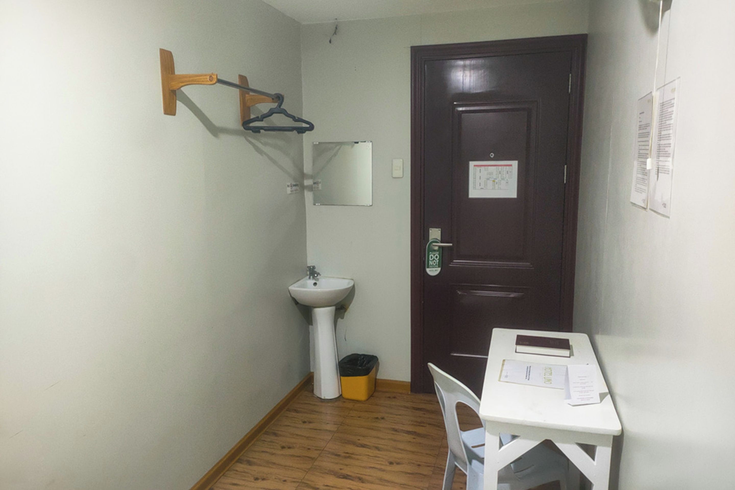 Um banheiro pequeno com pia, espelho e porta com placa de 'não perturbe'.