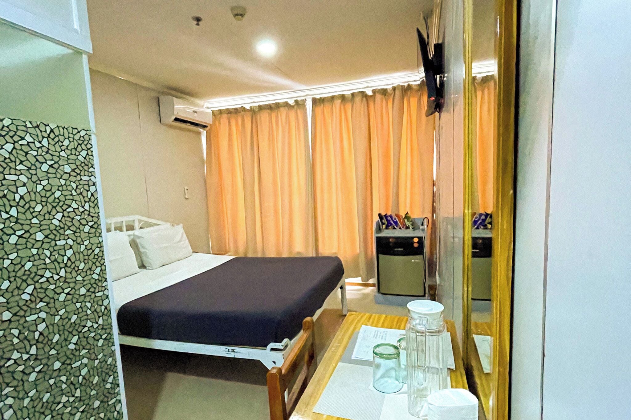 Quarto de hotel com uma cama, uma mesinha e um espelho.
