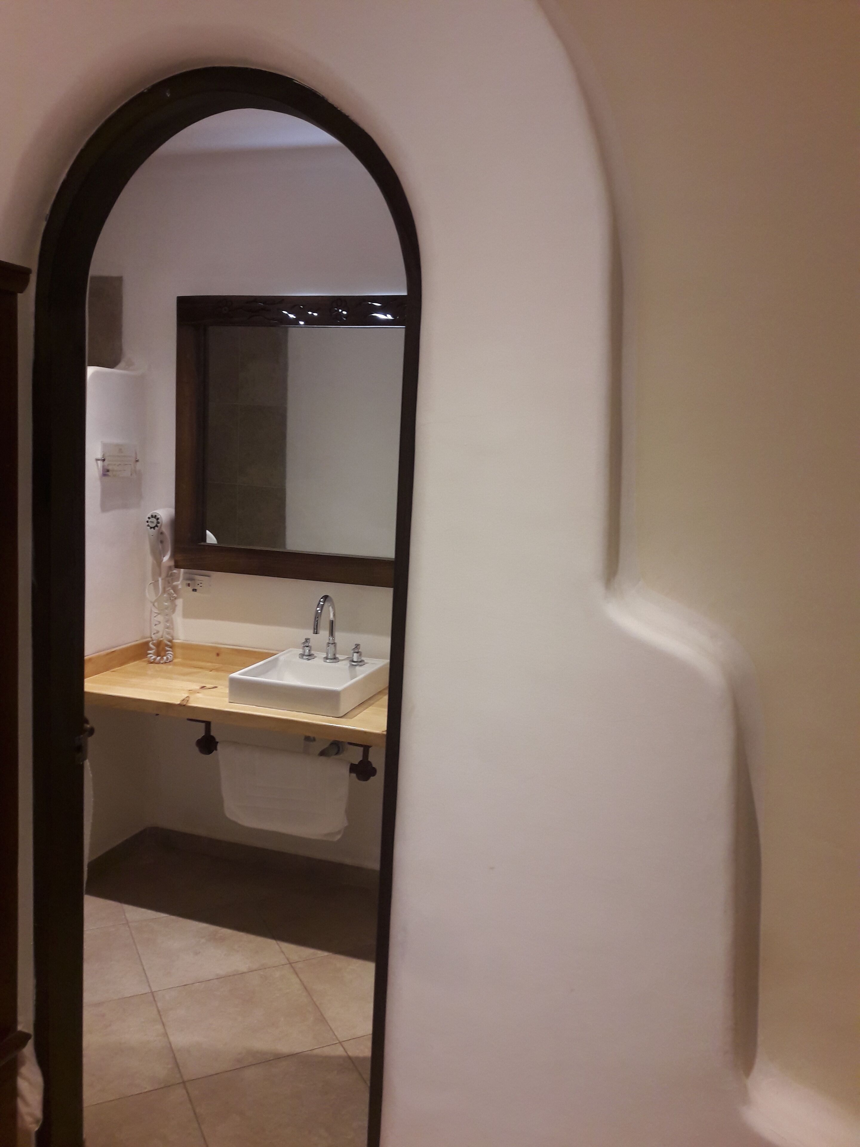 Uma casa de banho com uma pia branca, um espelho e uma toalha pendurada num porta-toalhas.