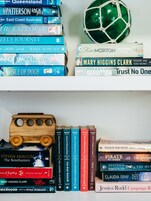 Duas estantes repletas de livros e um brinquedo de ônibus de madeira.