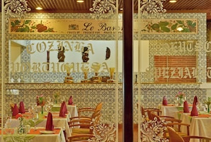 Interior de restaurante com decoração elaborada, um quadro de menu e mesas postas para refeições.