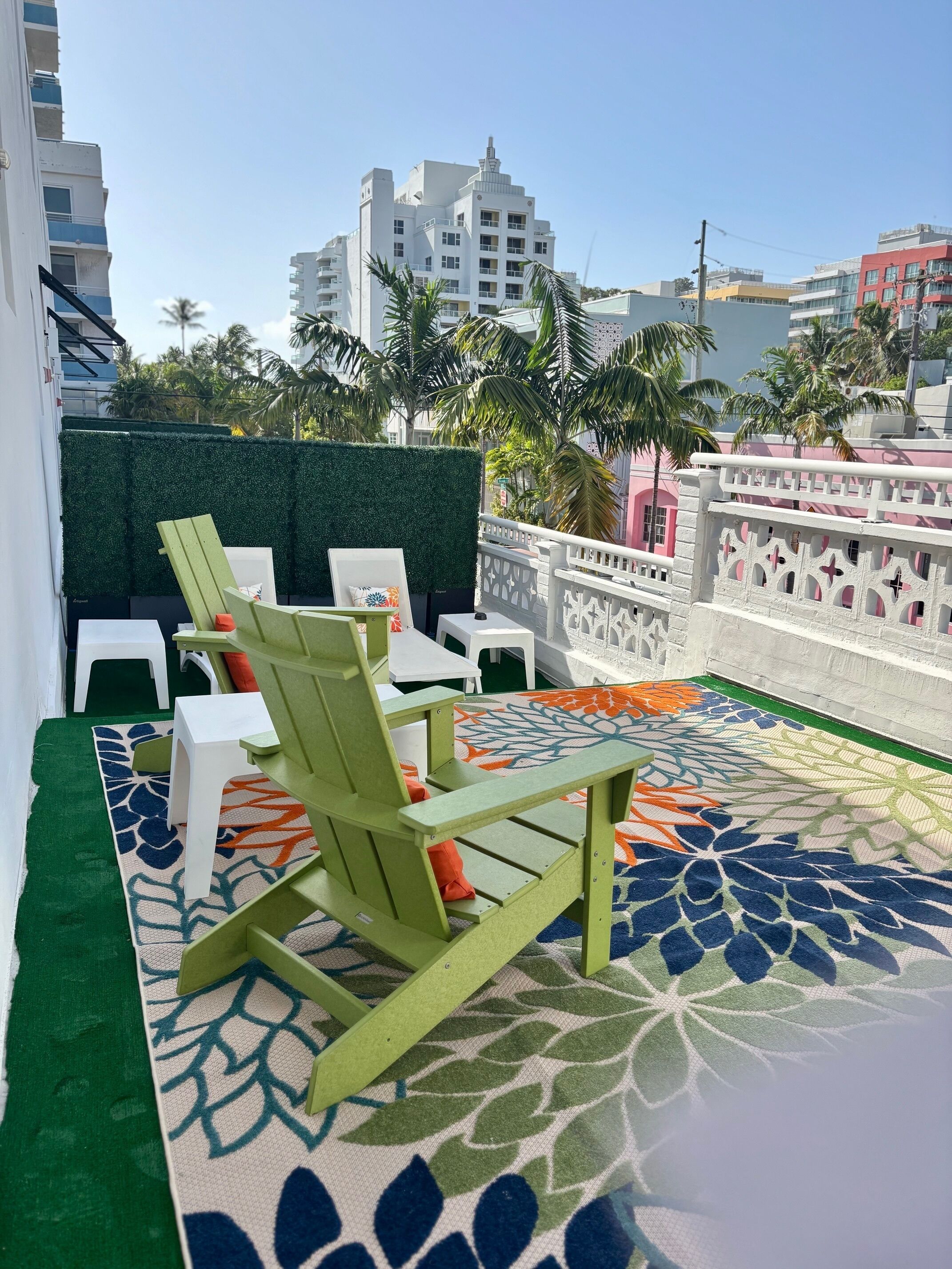 Um terraço no telhado com cadeiras verdes, uma mesa e um piso estampado.